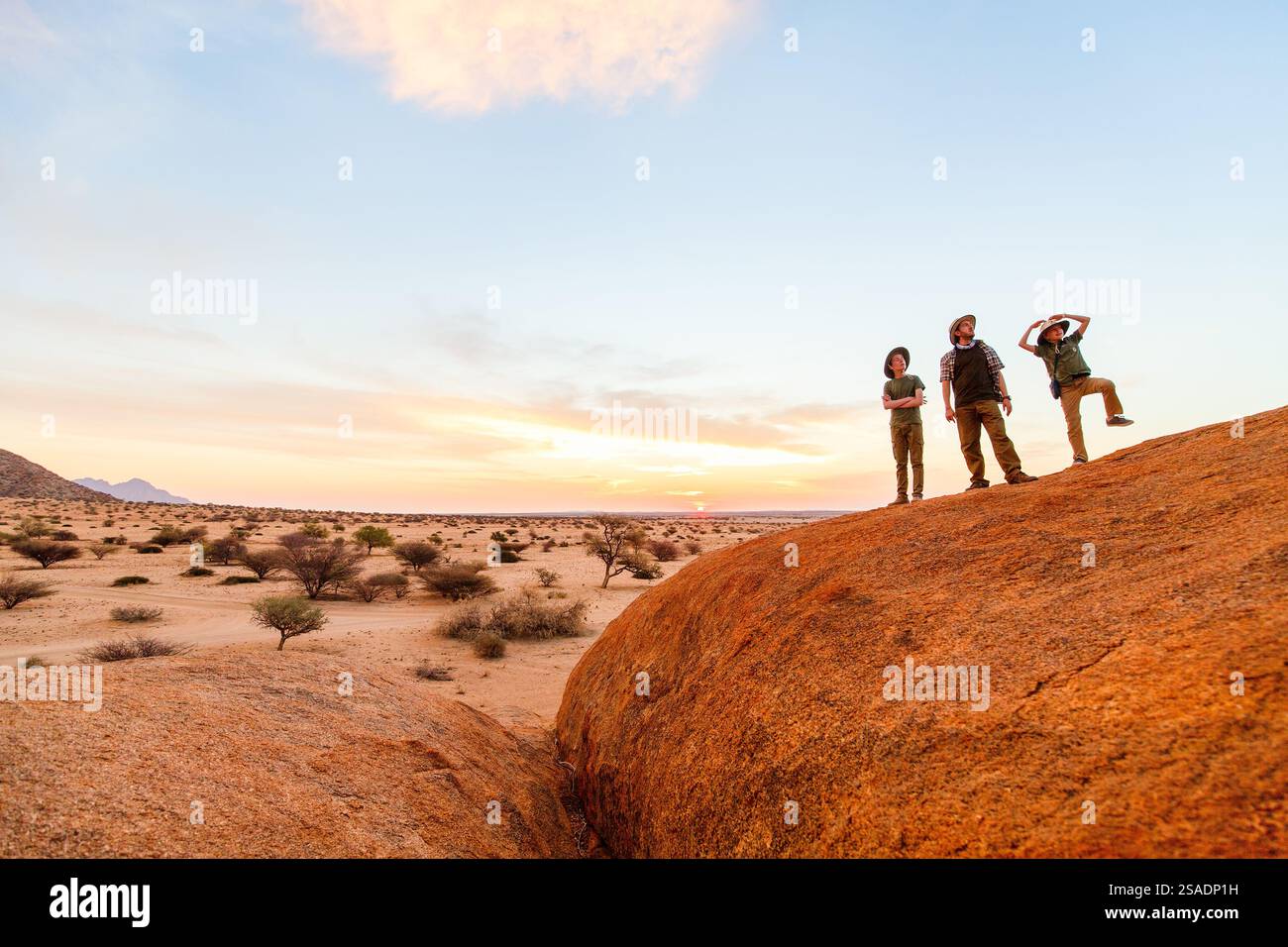 Family father and two kids hiking in Spitzkoppe area with unique rock formations in Damaraland ...