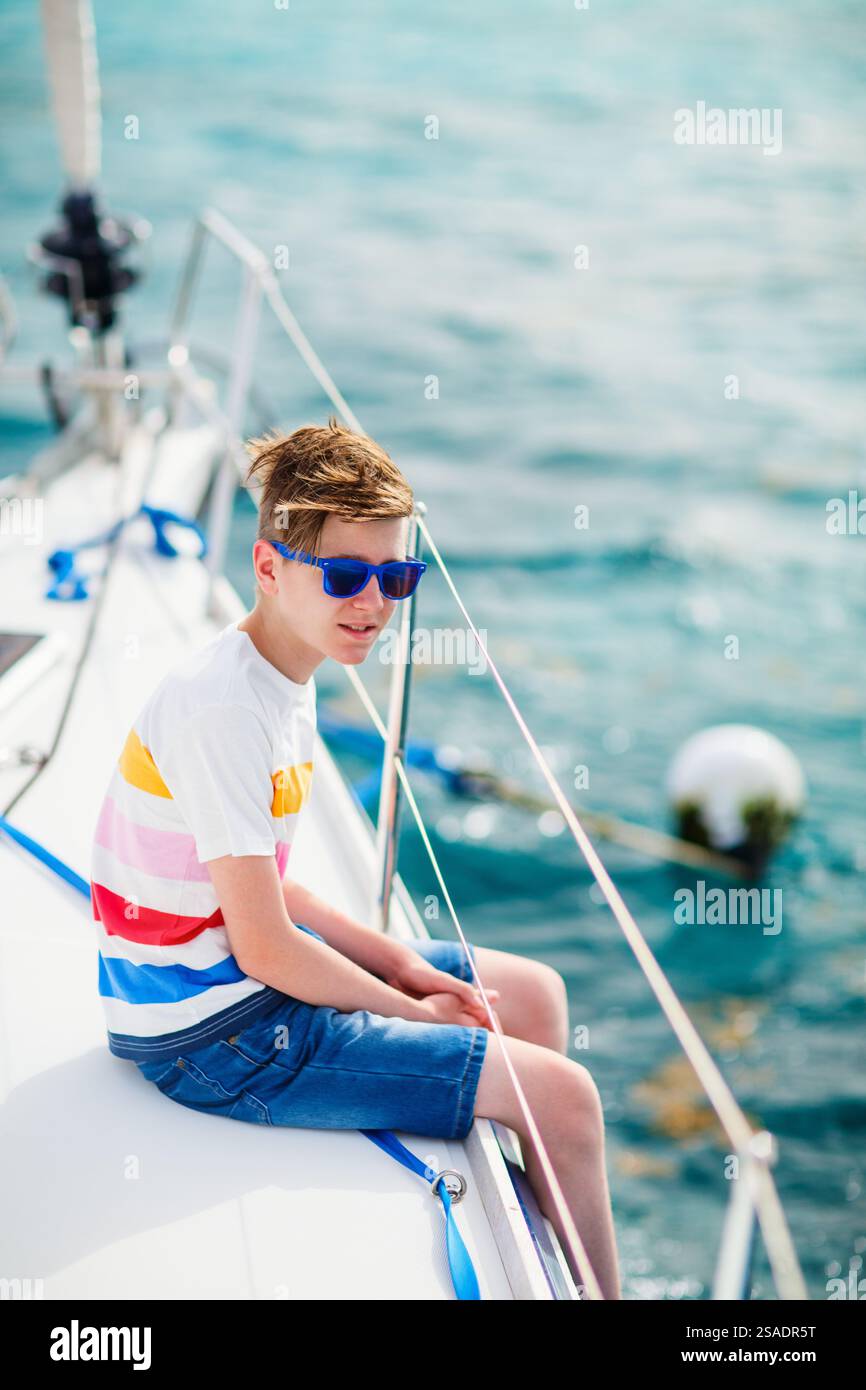 Teenage boy enjoying sailing on board a chartered catamaran or yacht ...