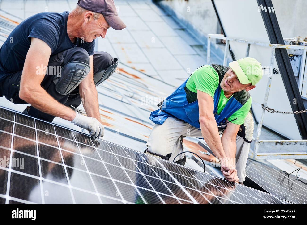 Workers building solar panel system on metal rooftop of house. Two men ...