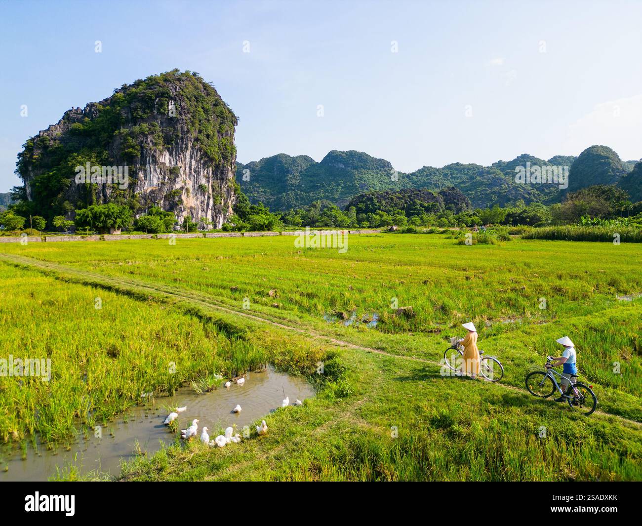 Beautiful couple exploring by bikes countryside and rice fields in Ninh ...