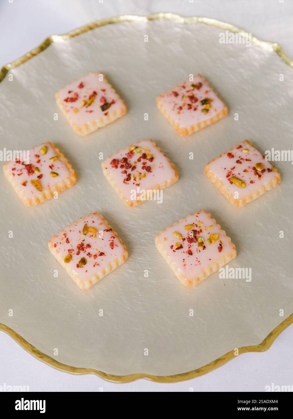 A delicate arrangement of square sweets is displayed on a shimmering ...