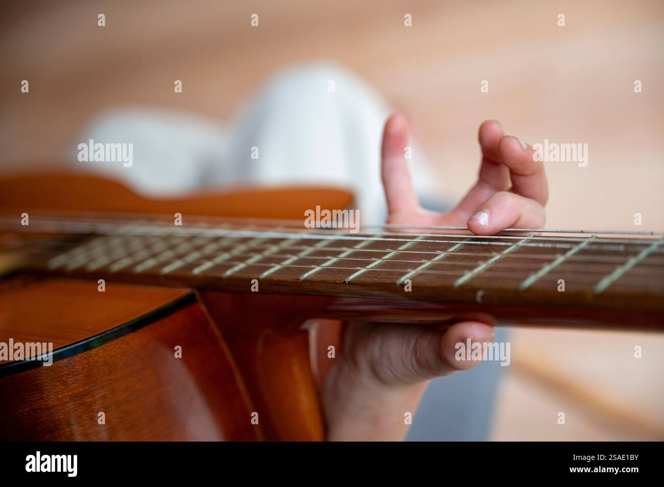 Closeup view of a child practicing playing guitar trying to learn a ...