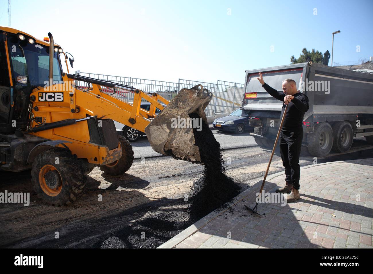Bulldozer pouring asphalt with it's loader on the scrubbed road to ...