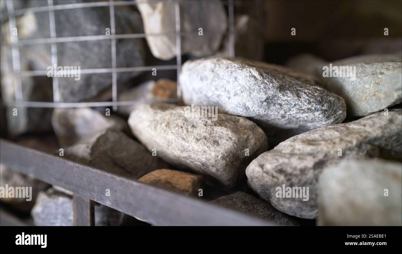 Gray stones for sauna stove are arranged on a metal grid and in a wire ...