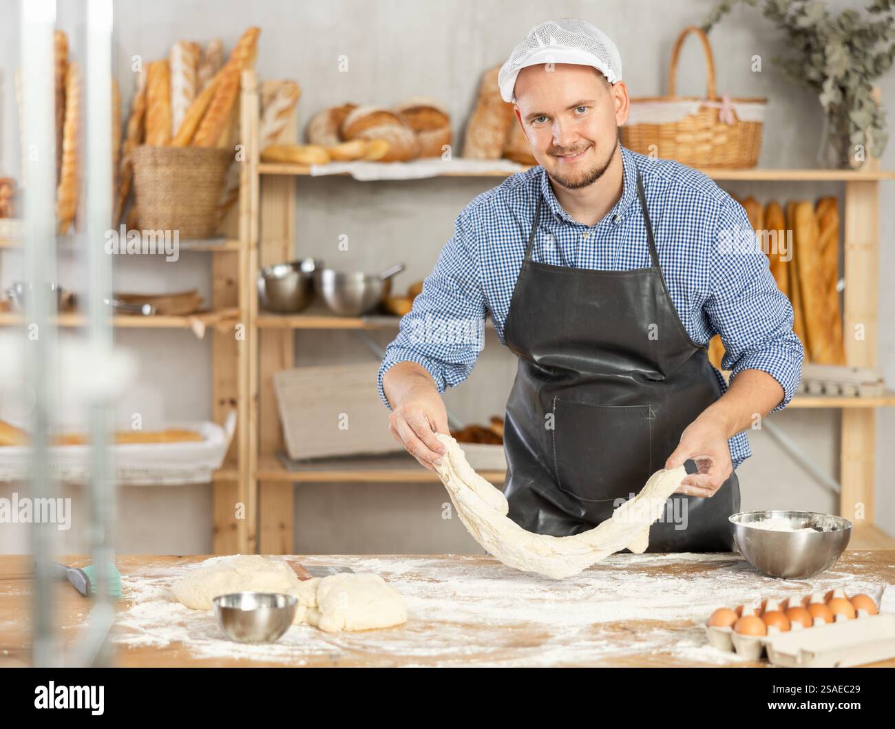 Guy works in bakery as baker, kneads dough, works with flour Stock ...