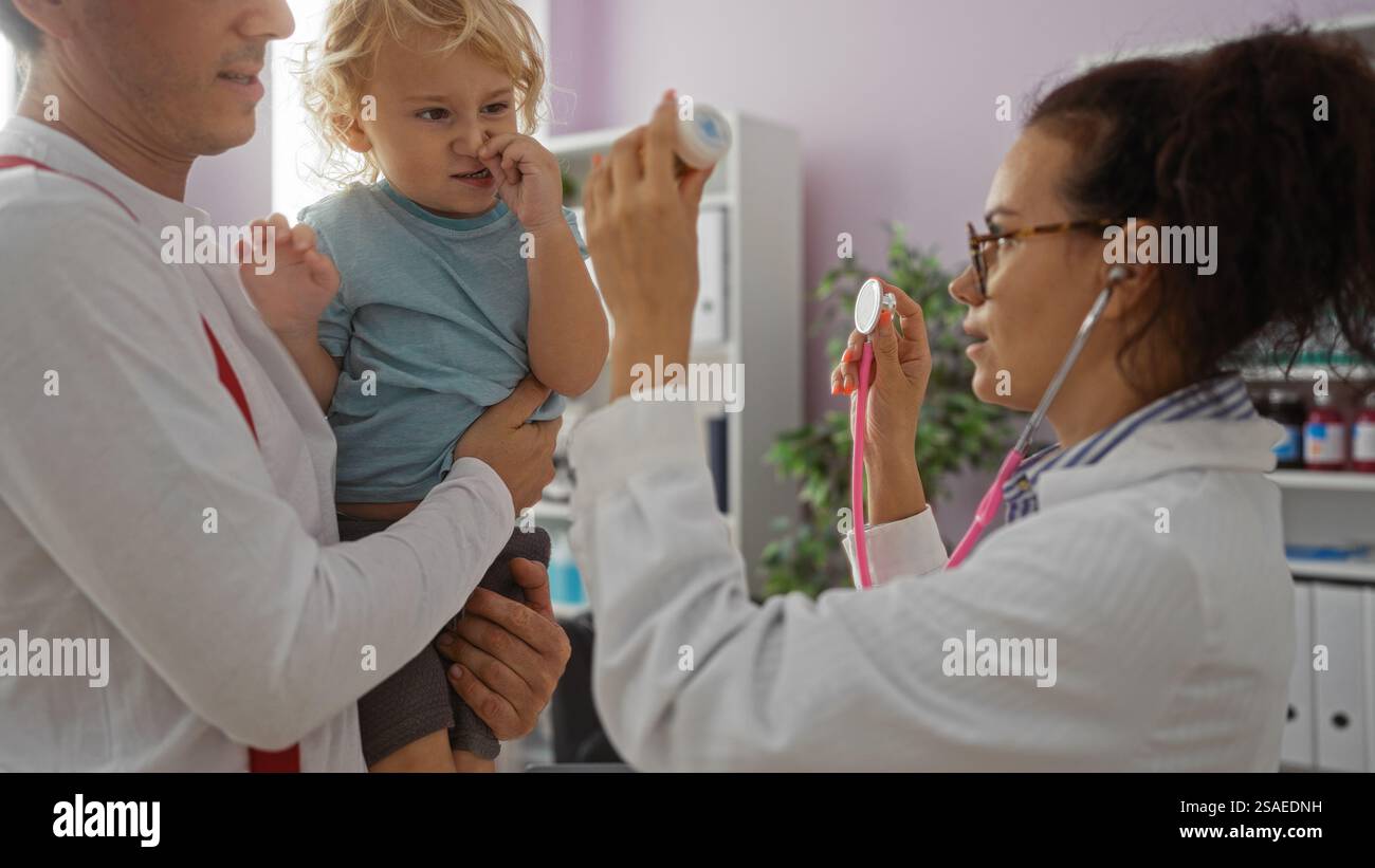 Doctor using stethoscope examines child held by man in clinic room ...