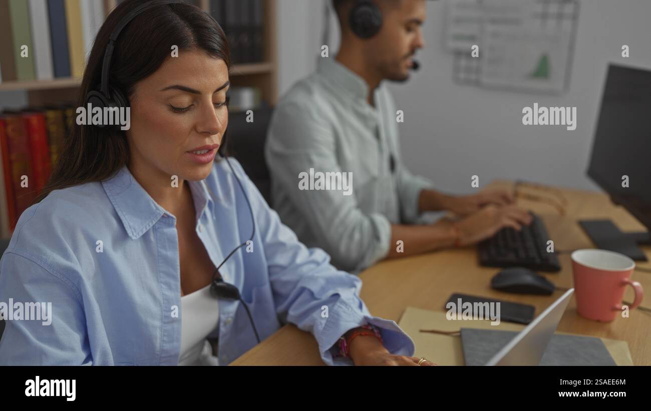 Woman and man working together in office using headsets on computers ...