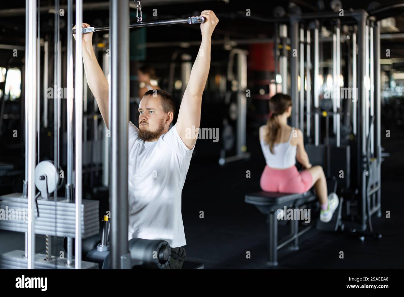 Young athletic man work out muscles of hands on cable crossover machine ...
