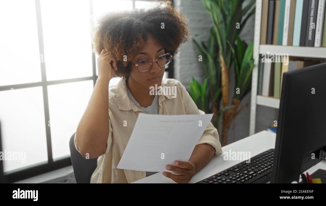 Woman reading paper with focus in office setting with large plant and ...