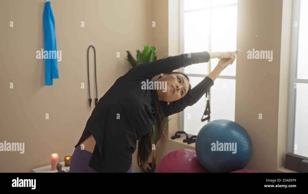 Young chinese woman stretching indoors in a sports center with gym ...