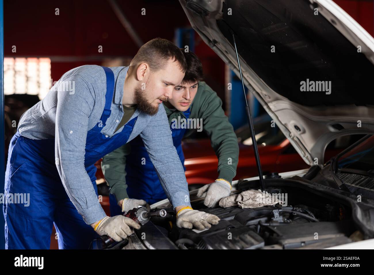 Two mechanics consult about repairing a car Stock Photo - Alamy