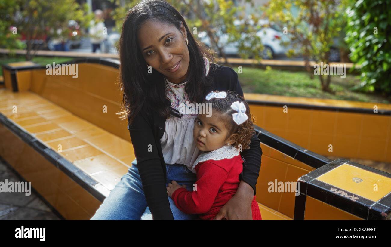 Mother embracing daughter in urban park setting with love, capturing family connection and ...