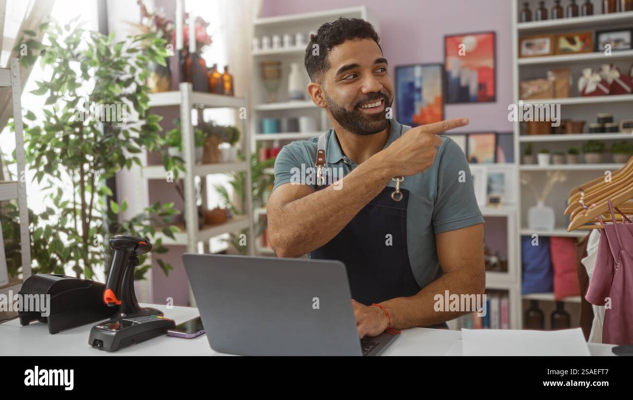 Young man in home decor store smiling and pointing while working at a ...