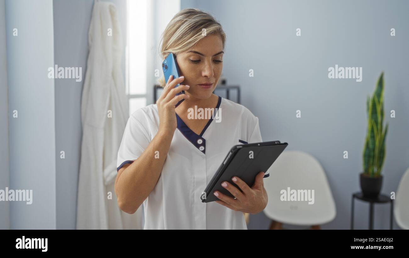 Woman working in a spa salon, talking on the phone while using a tablet ...