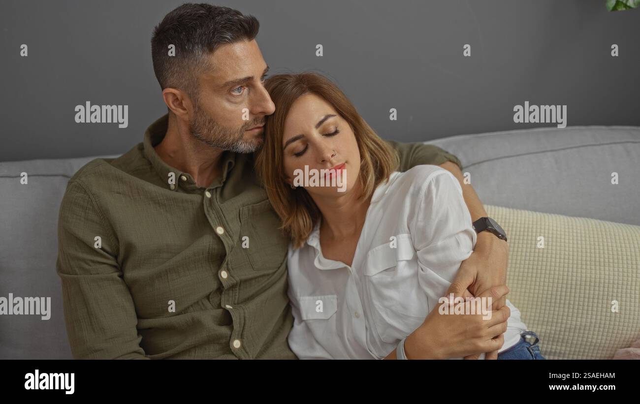 Couple sitting together on a couch in a cozy living room, woman resting ...