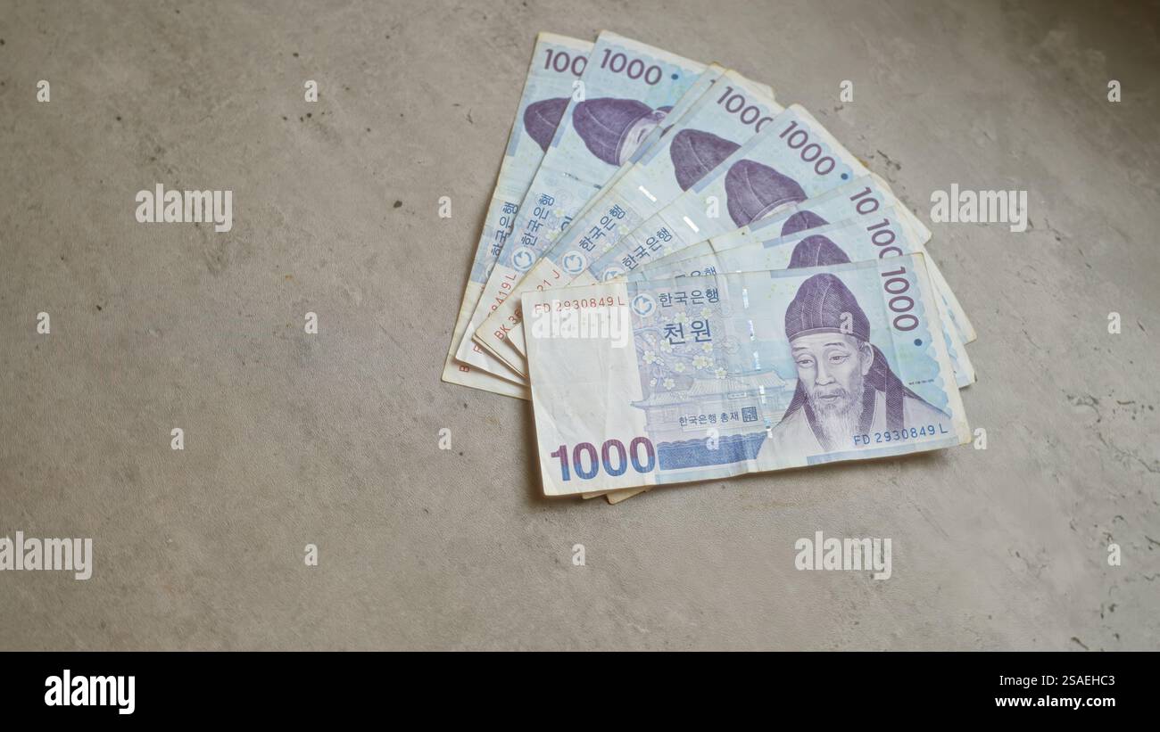 South korean banknotes scattered on a rough concrete surface ...