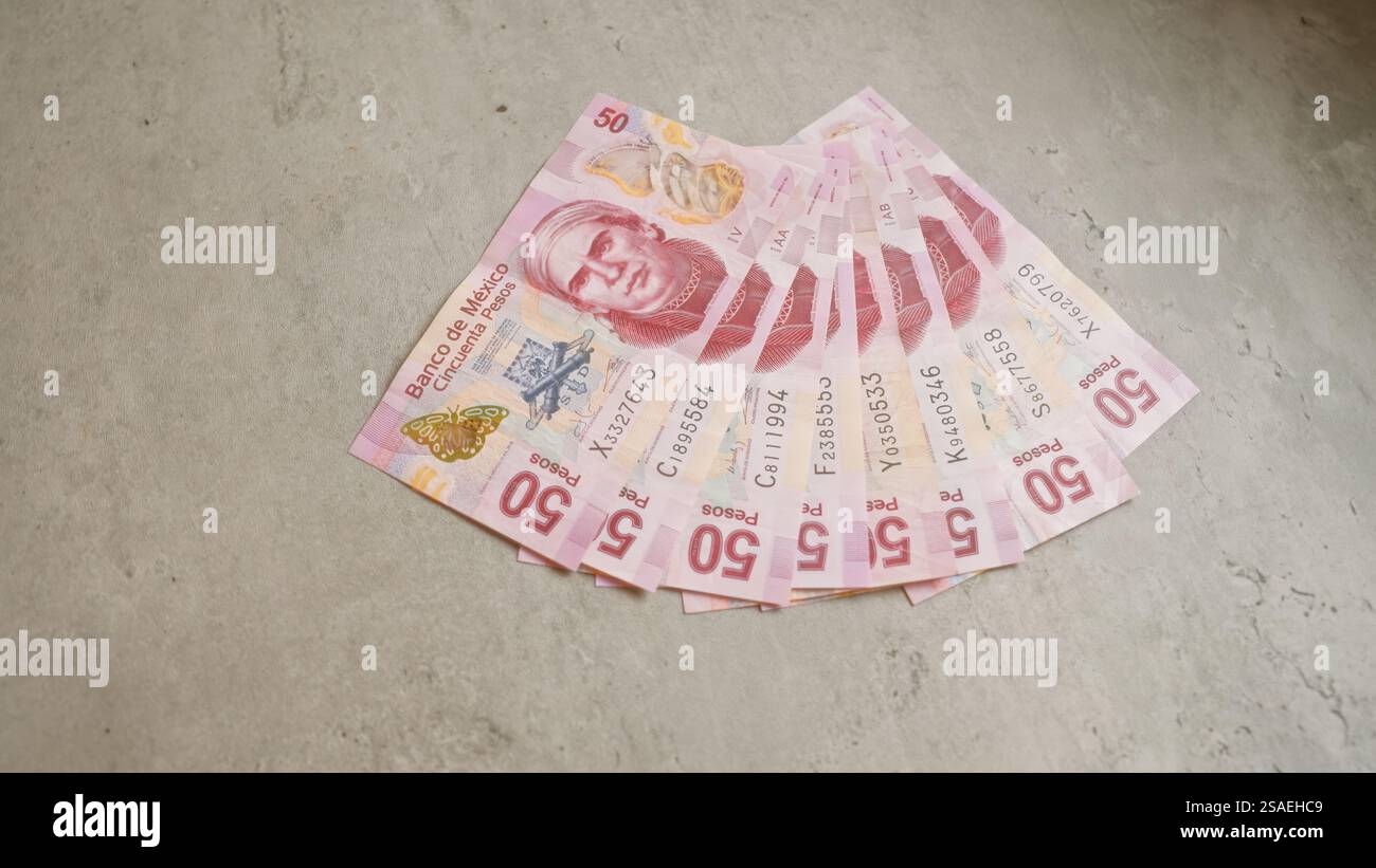 Multiple mexican 50 peso banknotes arranged on a concrete surface ...
