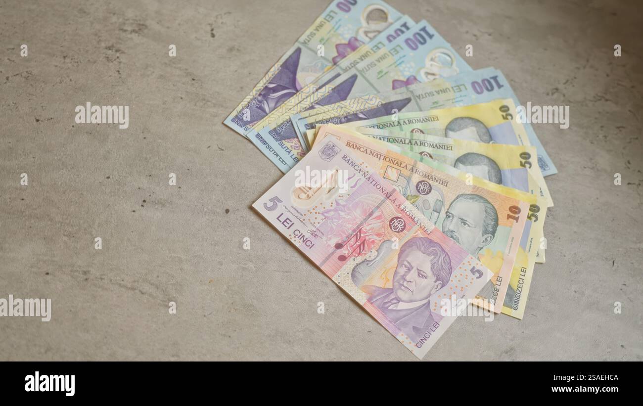 Romanian banknotes of various denominations lie scattered on a concrete ...