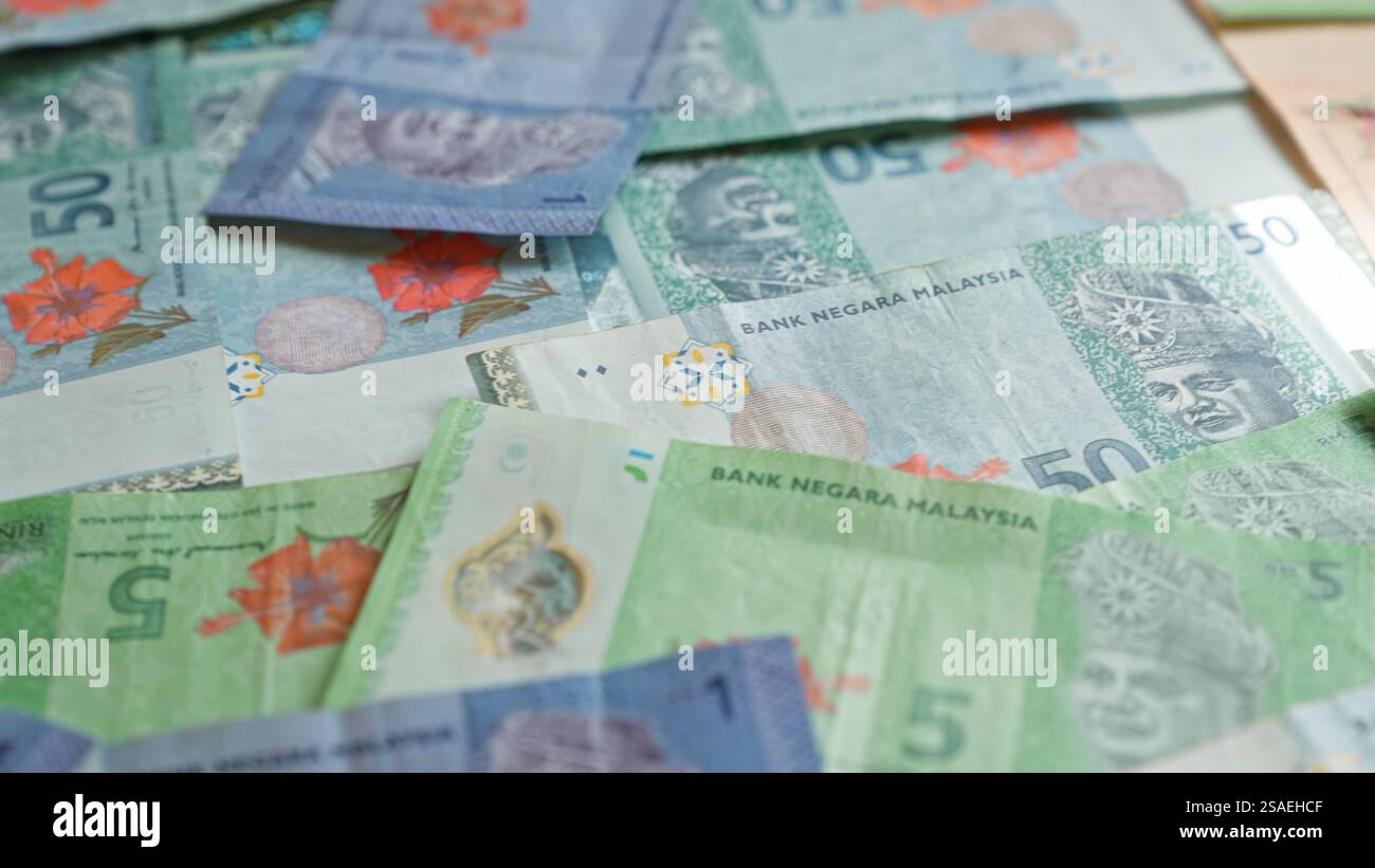 Malaysian banknotes of various denominations are scattered closely ...