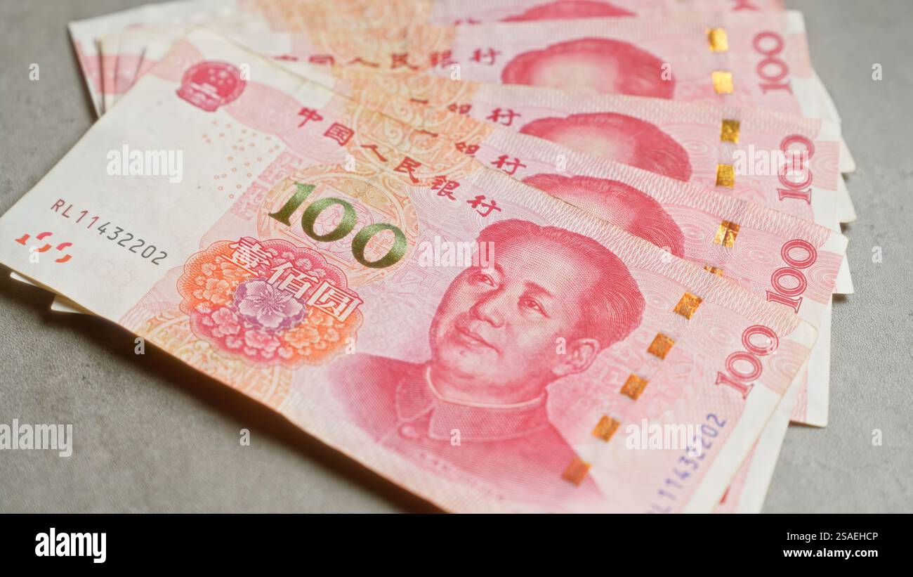 Chinese yuan banknotes spread on a concrete surface, depicting close-up ...