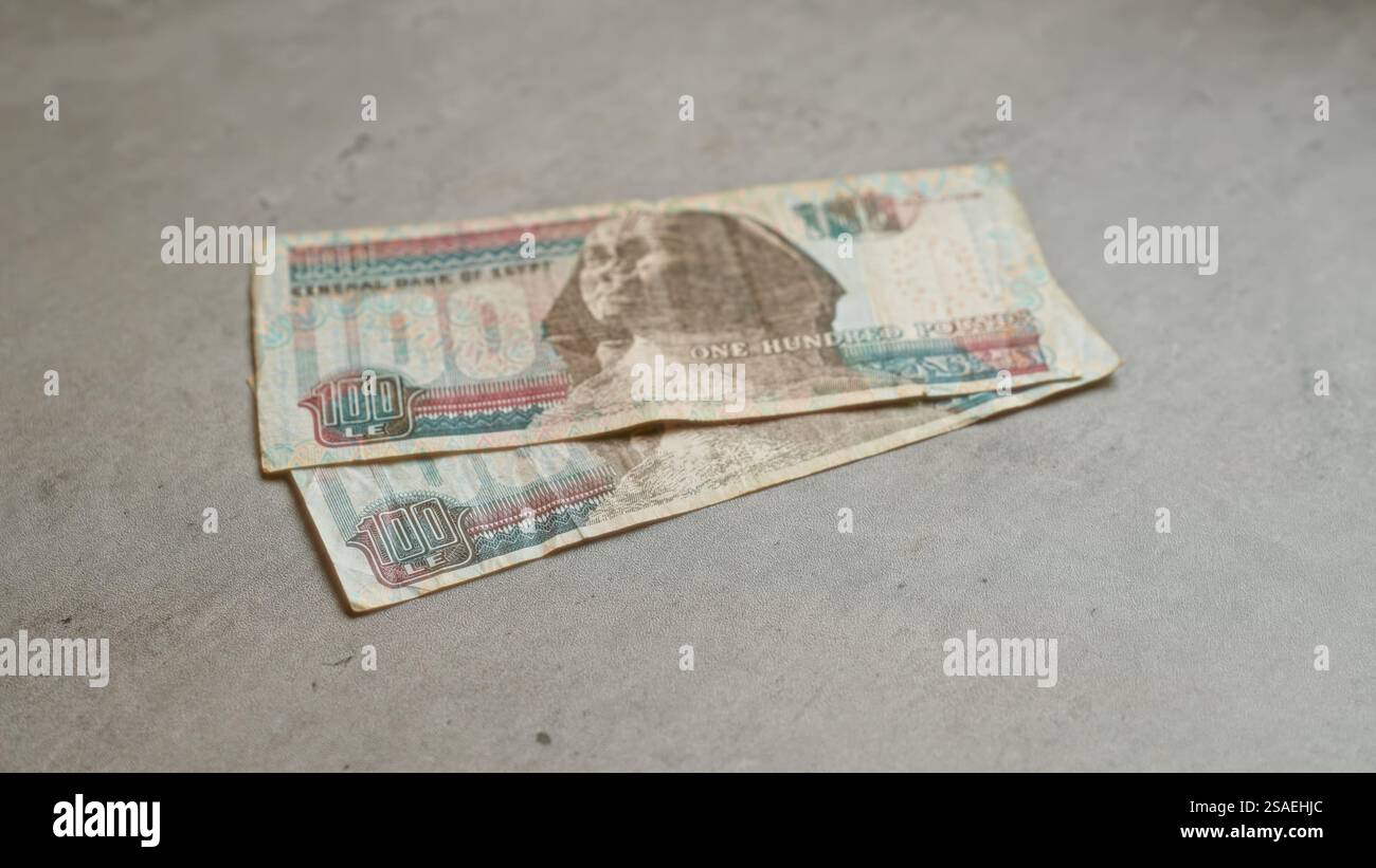 Egyptian hundred-pound banknotes lying on a concrete surface, depicting ...