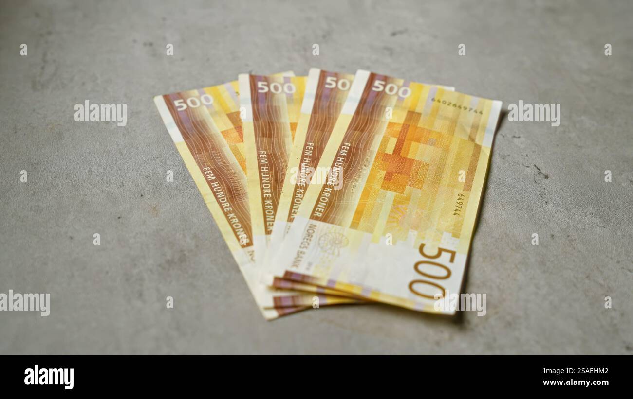 Norwegian 500 kroner banknotes spread on a smooth grey concrete surface ...