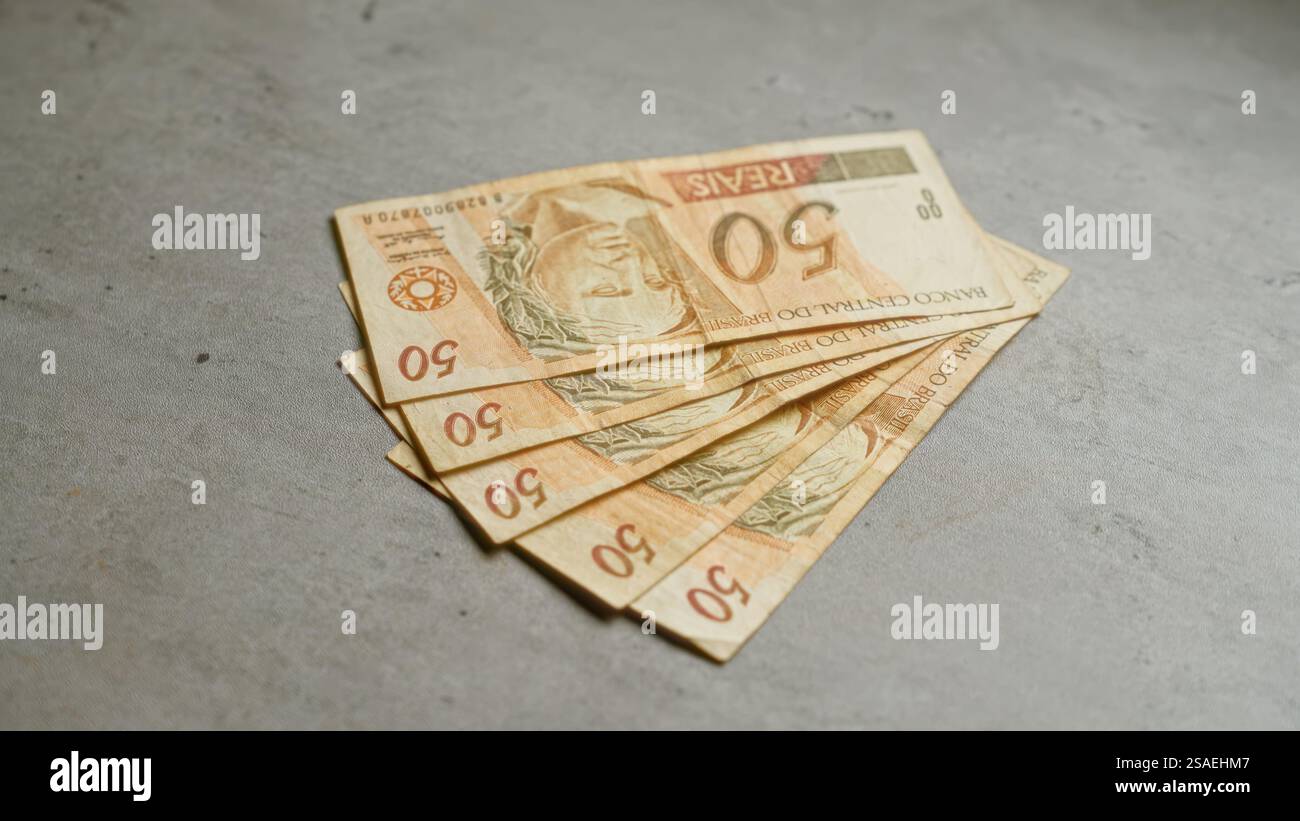 Brazilian 50 real banknotes scattered on a concrete surface showcase ...