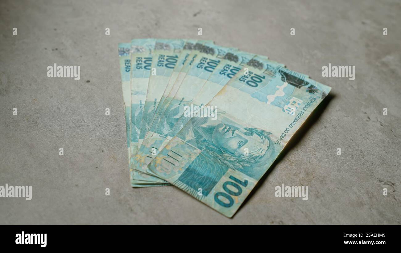 Brazilian banknotes of 100 reais laid out on a concrete surface ...