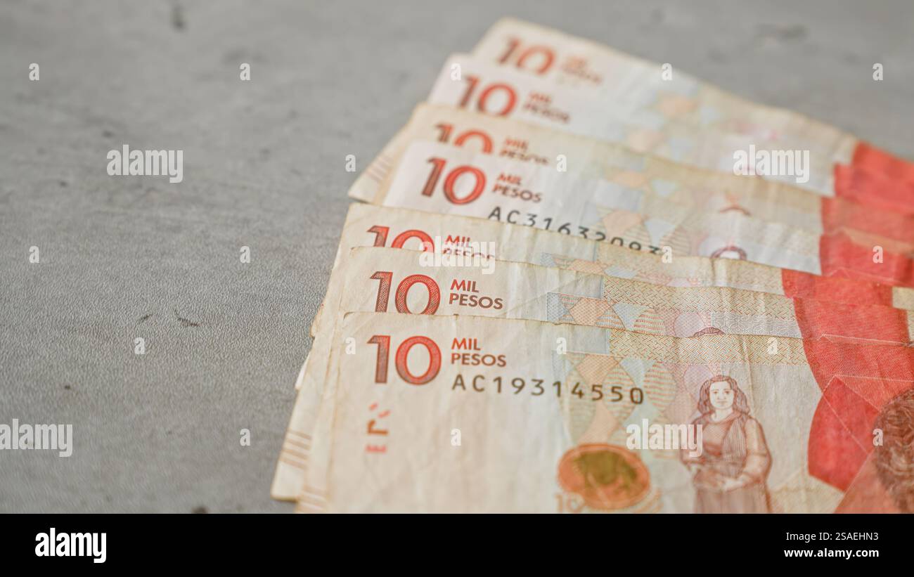 Colombian banknotes of ten thousand pesos laid out on a concrete ...