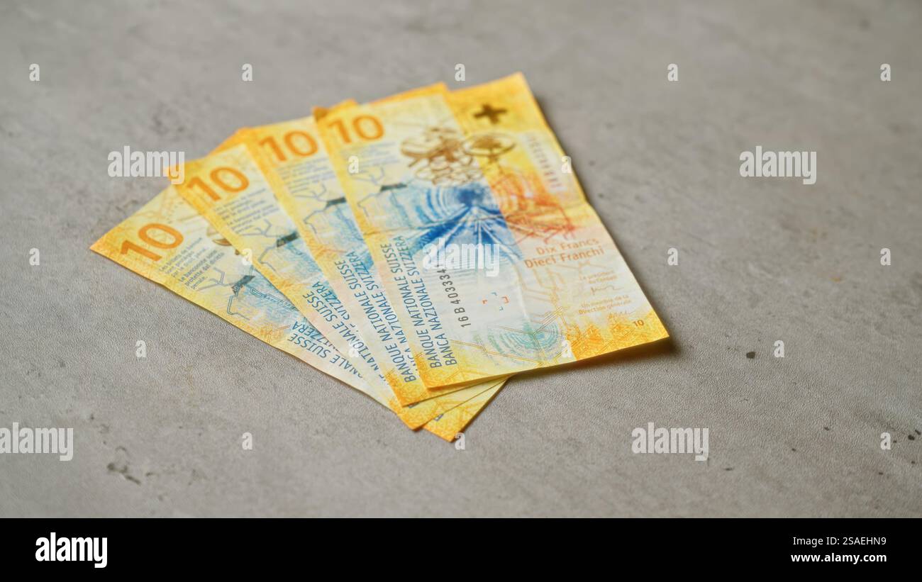 Swiss ten franc banknotes lie on a concrete surface, showcasing vibrant ...