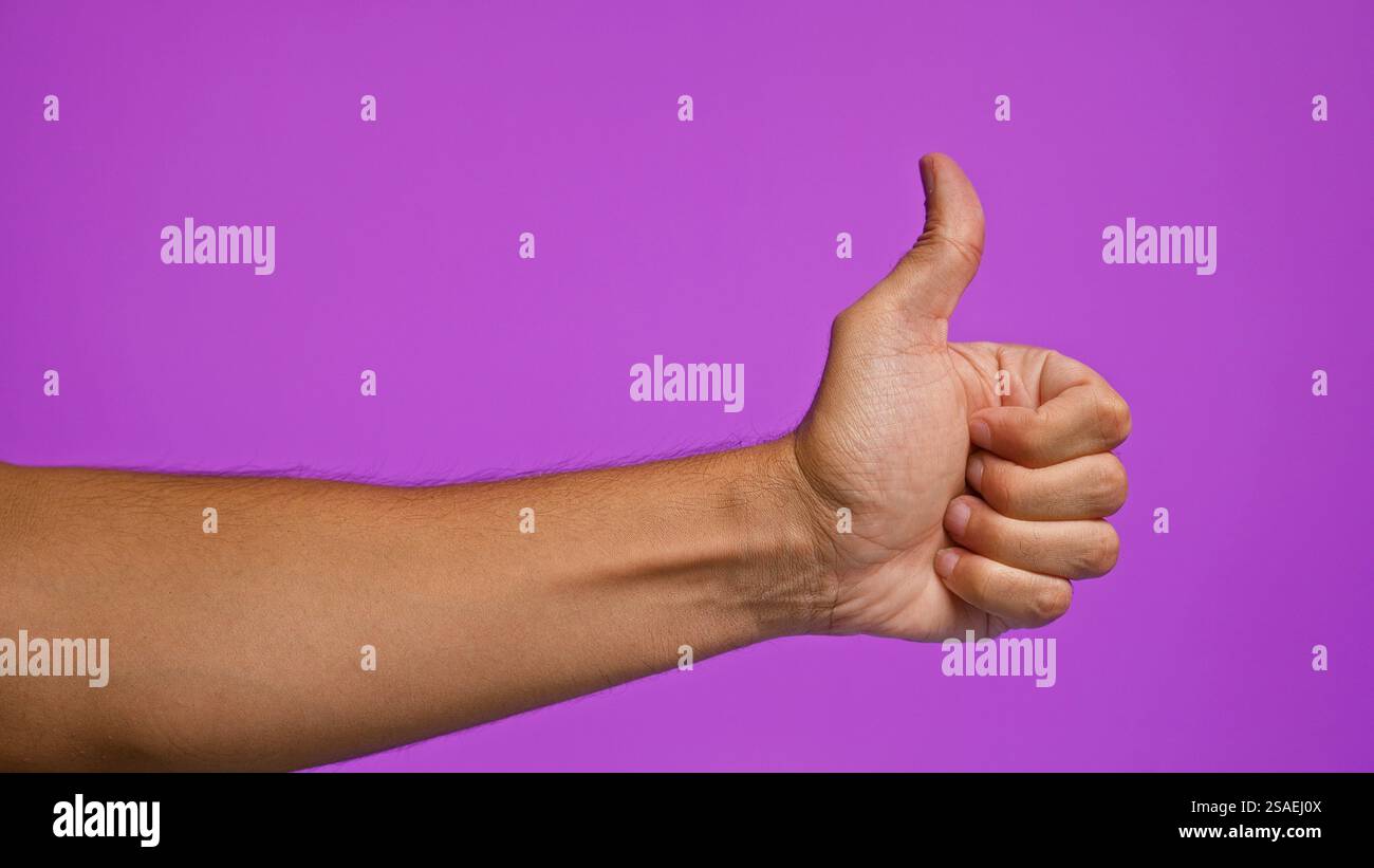 Man's hand giving a thumbs-up gesture against a vibrant purple ...