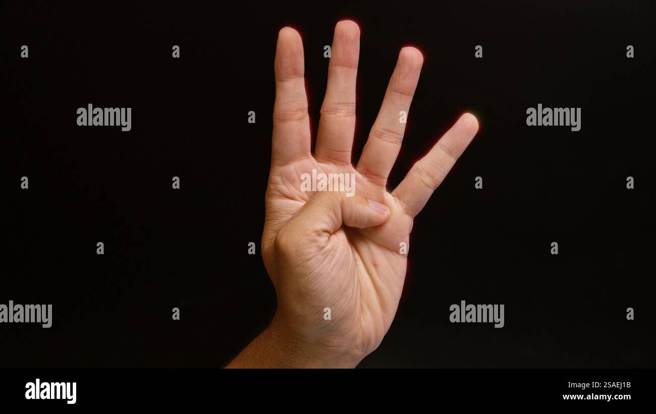 Man showing four fingers against a dark background, emphasizing the ...