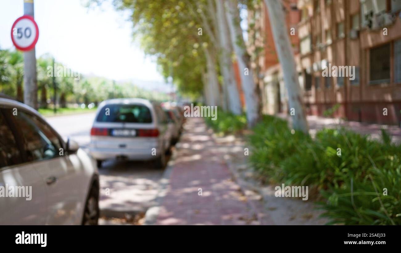 Blurry outdoor street scene with defocused cars parked along a blurry ...