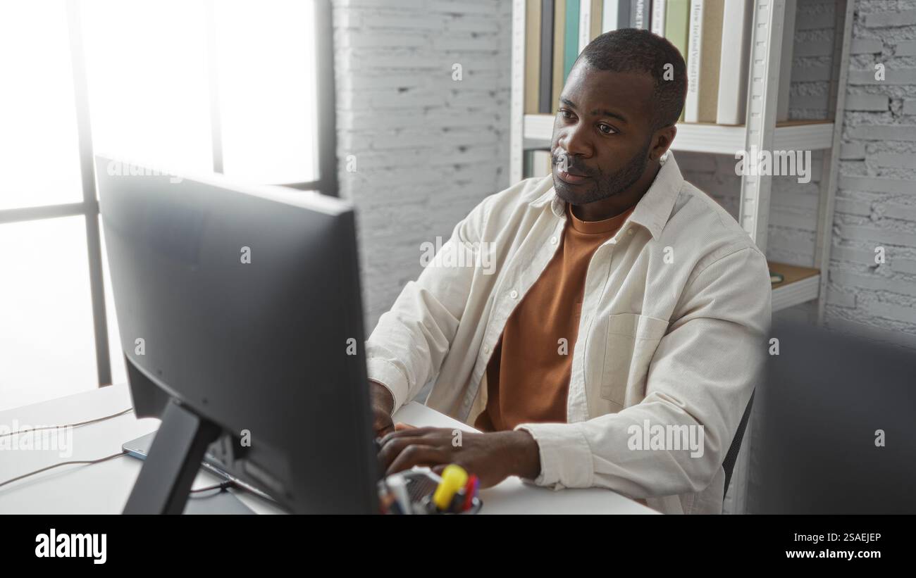 Young african man working in an office environment, focused on his ...