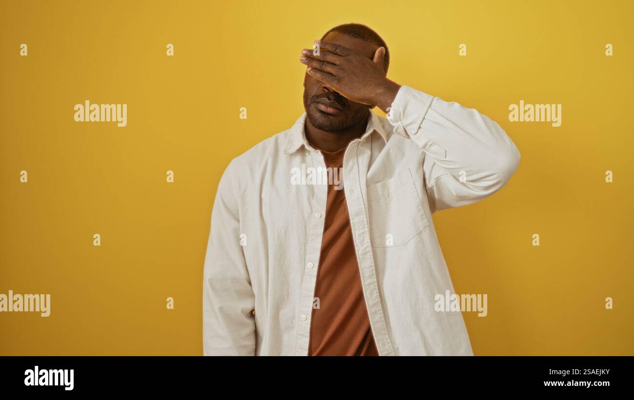 Young, black, man covering his face with one hand isolated against a ...