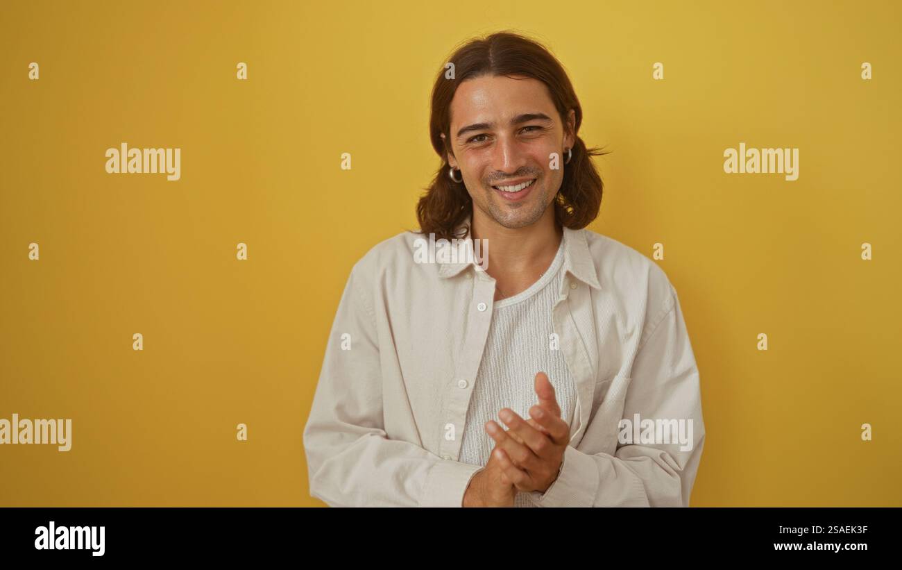Handsome young hispanic man with long hair smiling and clapping over an ...