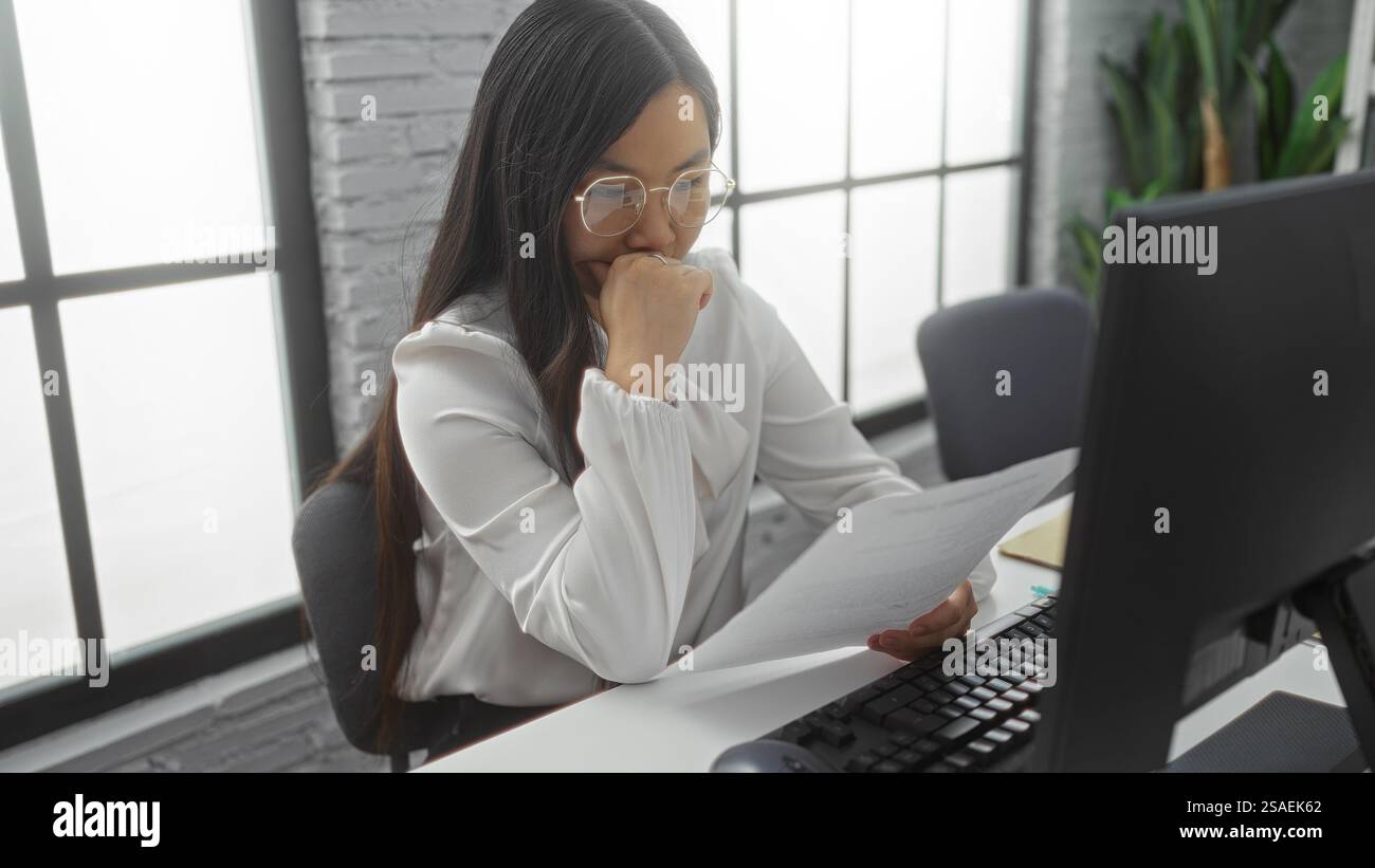 Woman reading document in office with computer, asian female focused on ...
