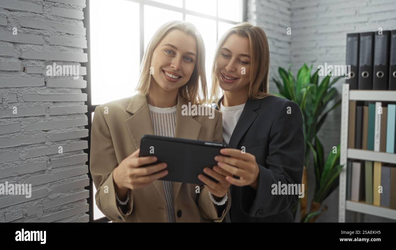 Women smiling in office setting, examining tablet, showcasing teamwork ...