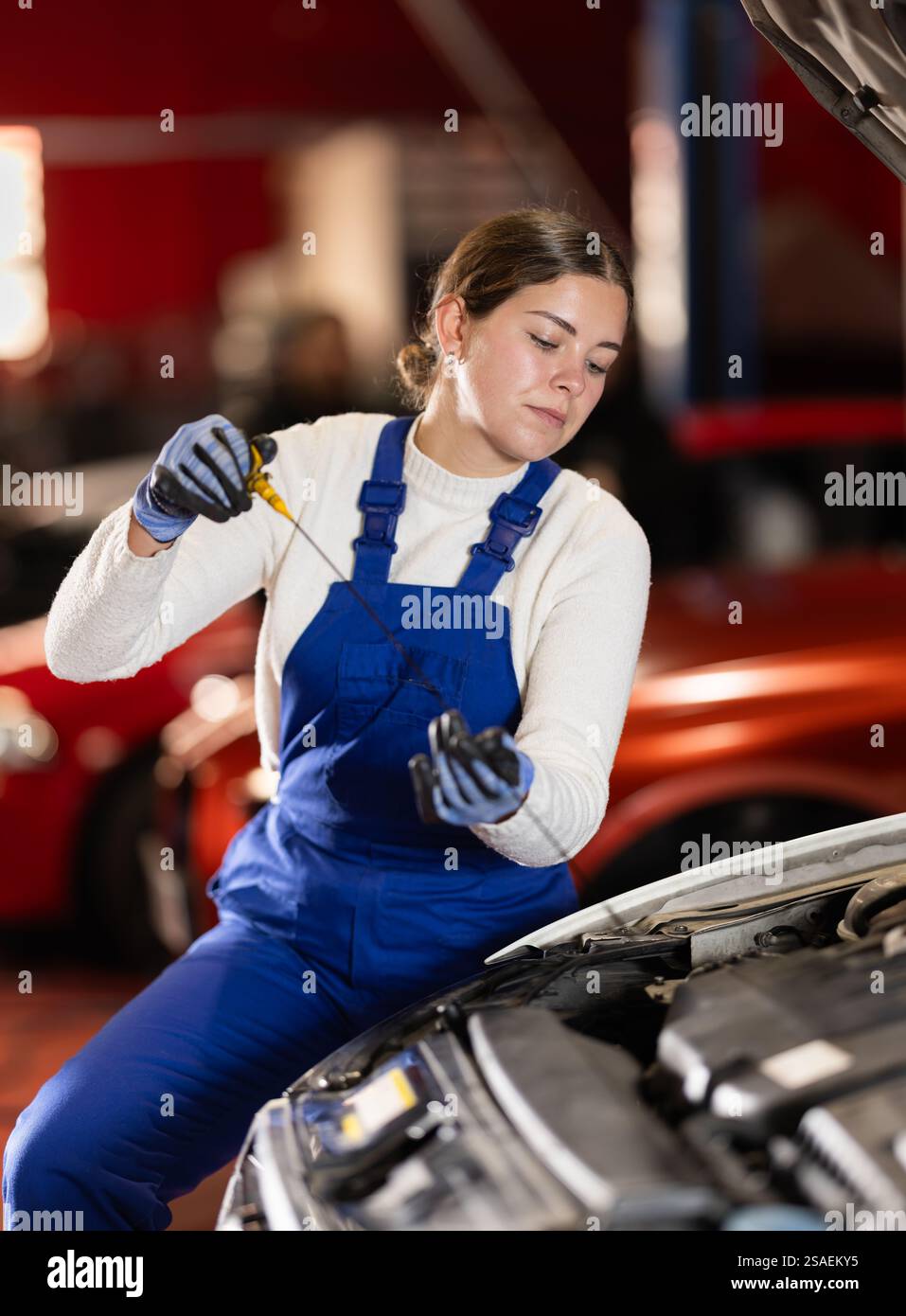 Female auto mechanic checking oil level in car engine Stock Photo - Alamy