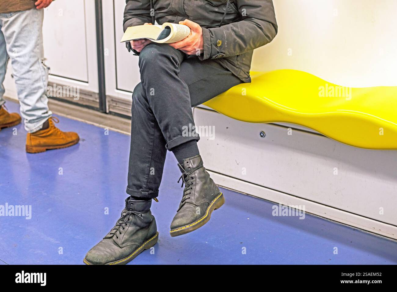 man in the subway sitting reading a book Stock Photo - Alamy