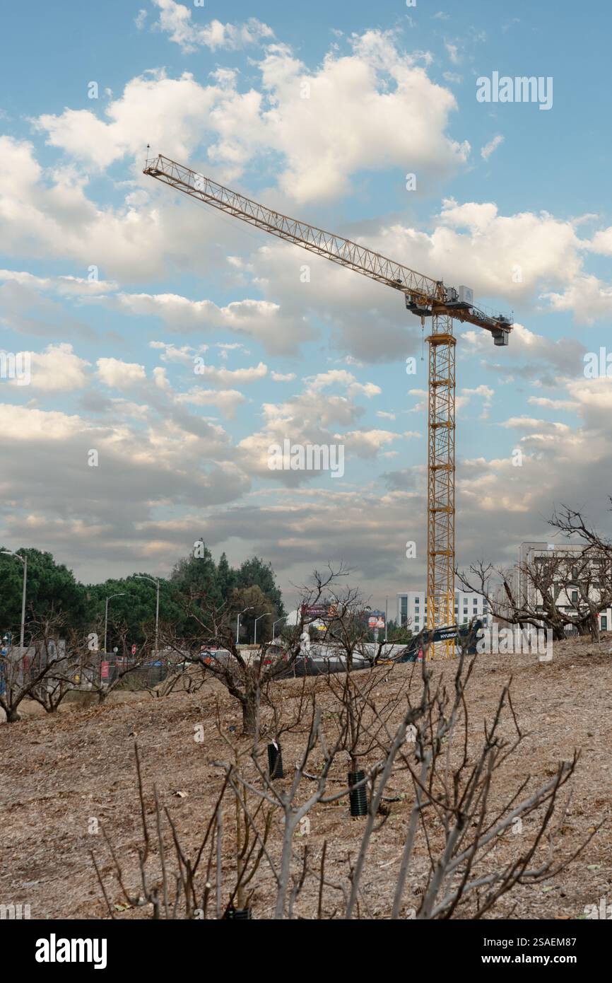 Tall crane at construction site against blue sky with white clouds ...