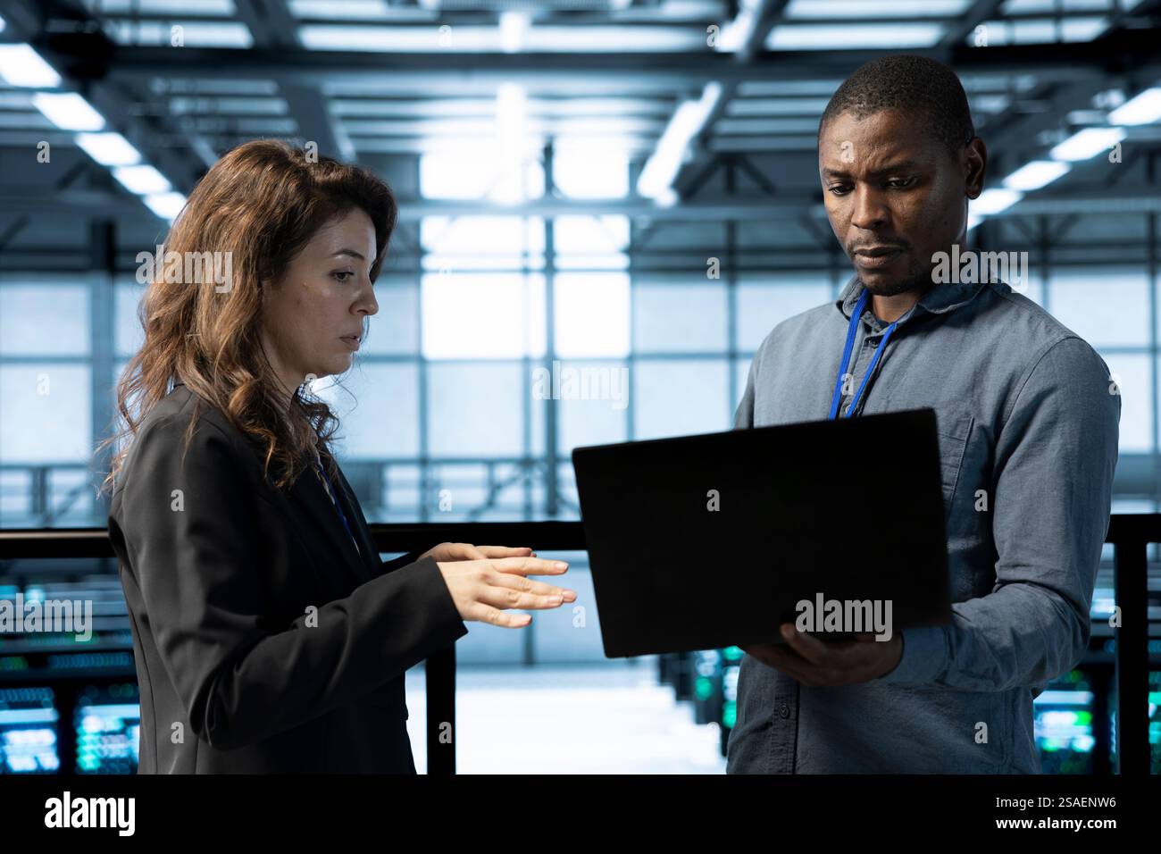 Data center programmer and colleague using laptop, conducting security audits, preventing errors ...