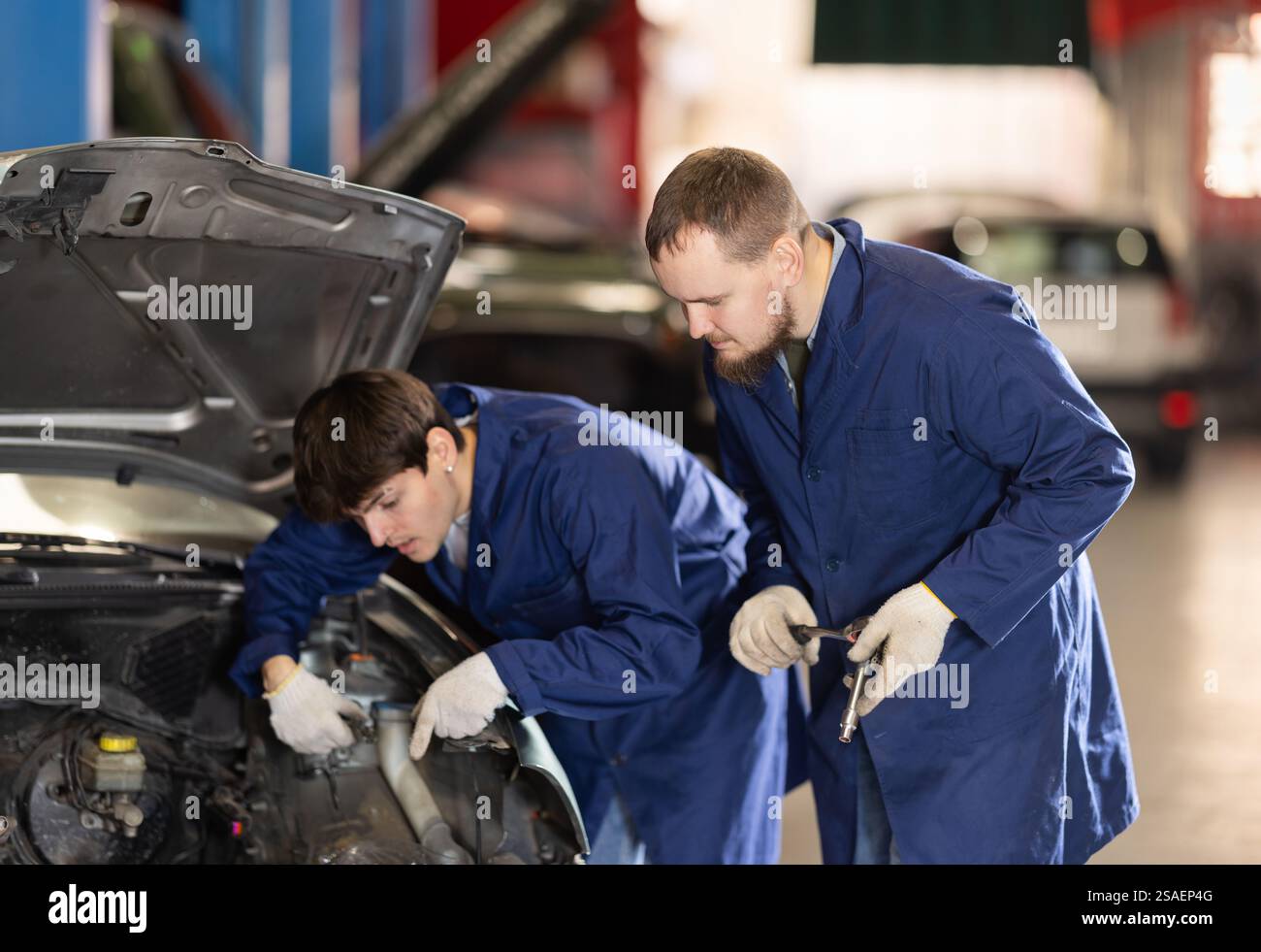 Two auto mechanics work together to diagnose an engine under the hood ...