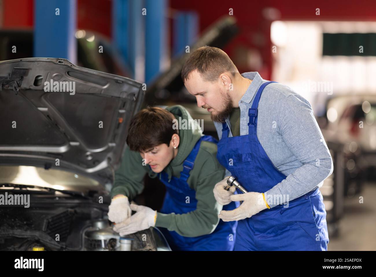 Two auto mechanics work together to diagnose an engine under the hood ...