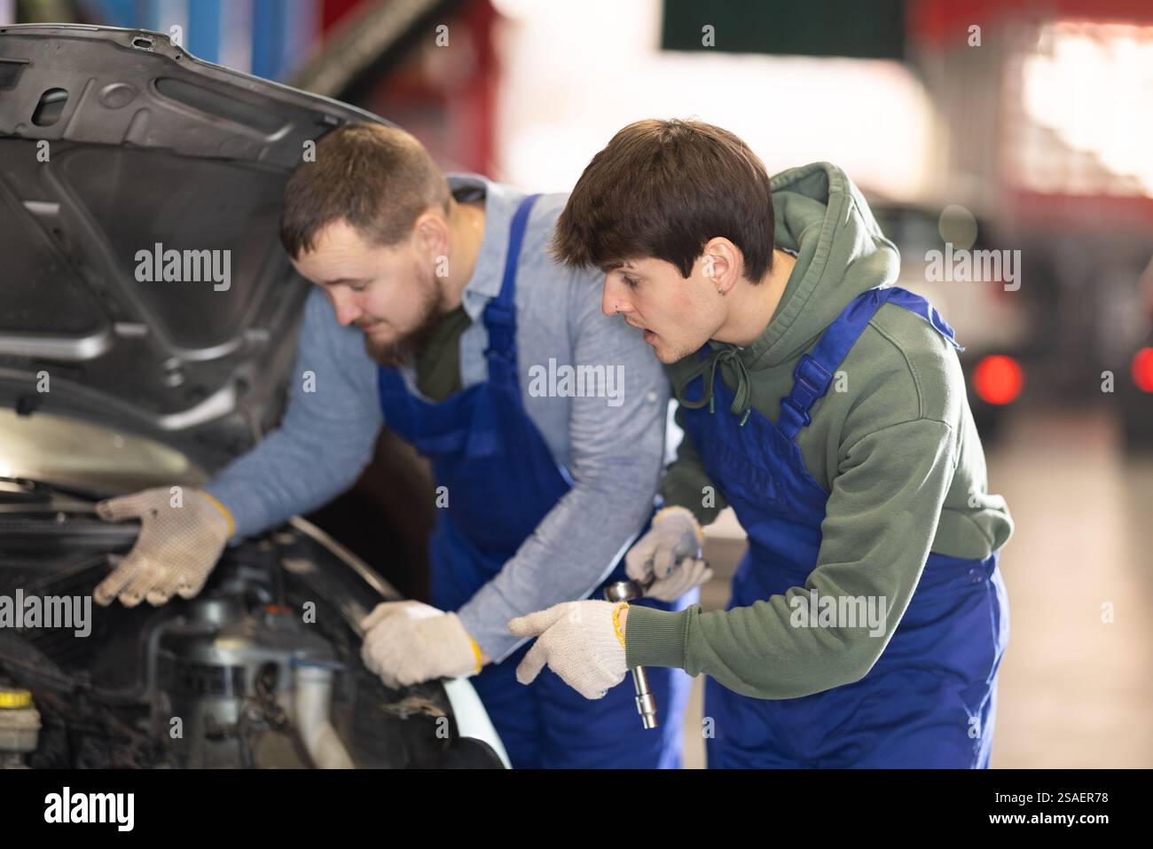 Two mechanics fixing a broken car in a service station Stock Photo - Alamy