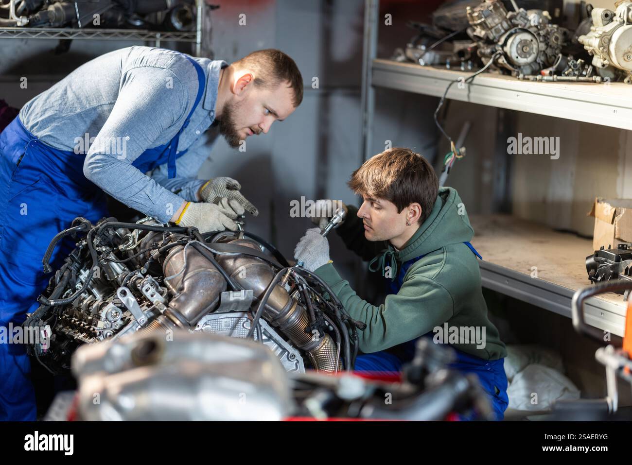 Two mechanics disassemble the engine and fix it Stock Photo - Alamy
