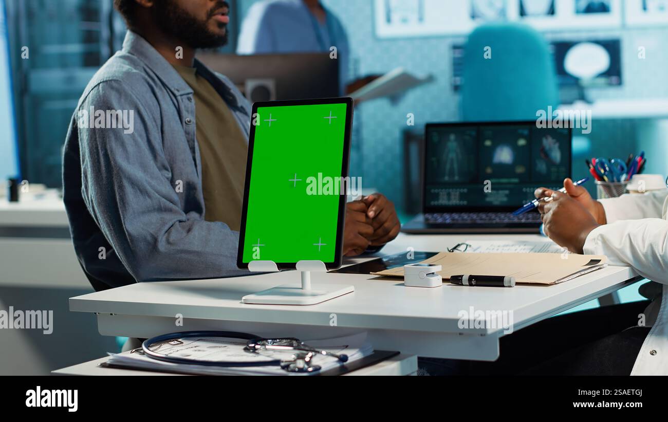 Black medic meets with patient next to isolated mockup display at the ...