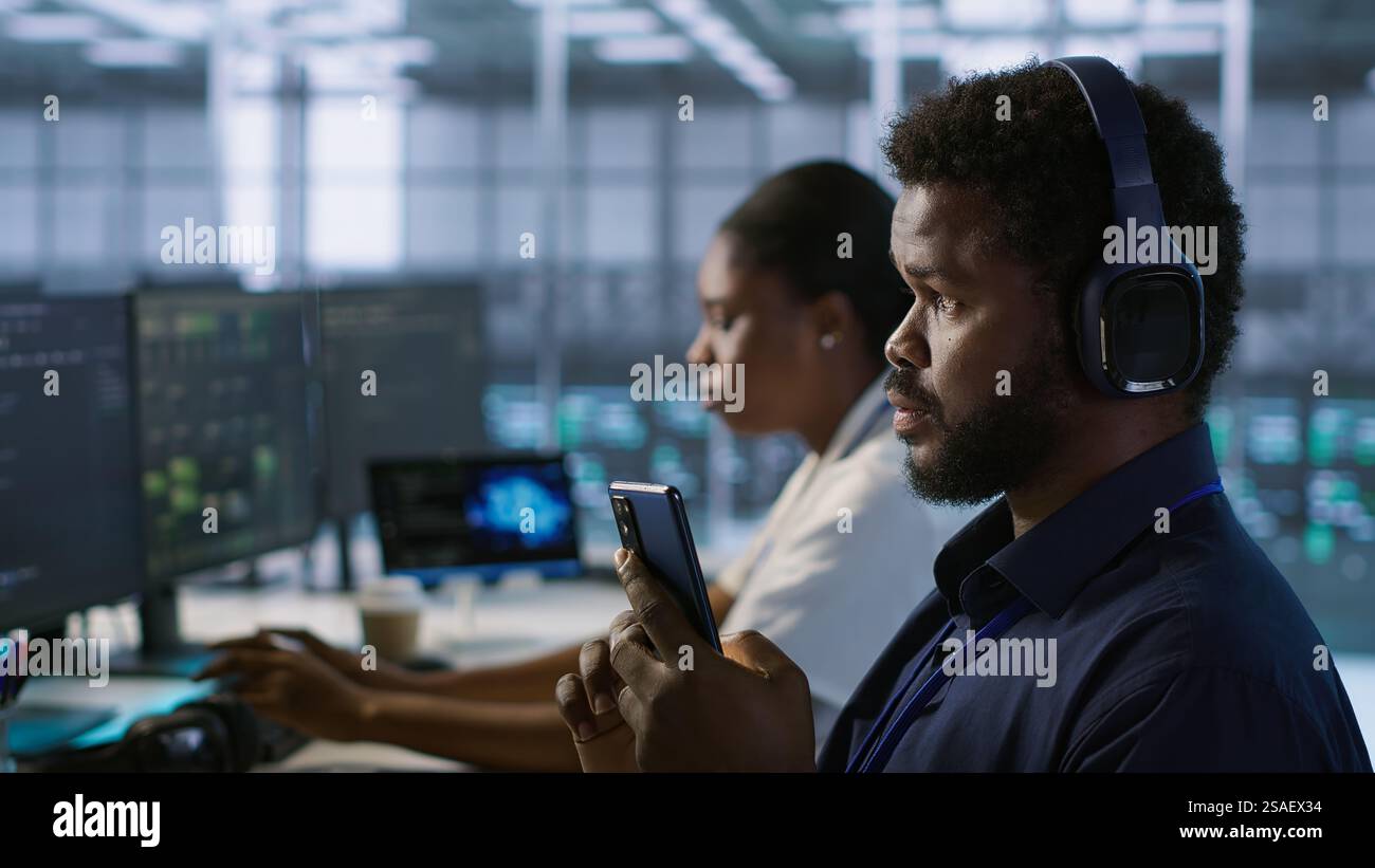 Worker in data center wearing headphones taking break from implementing AI systems, using ...