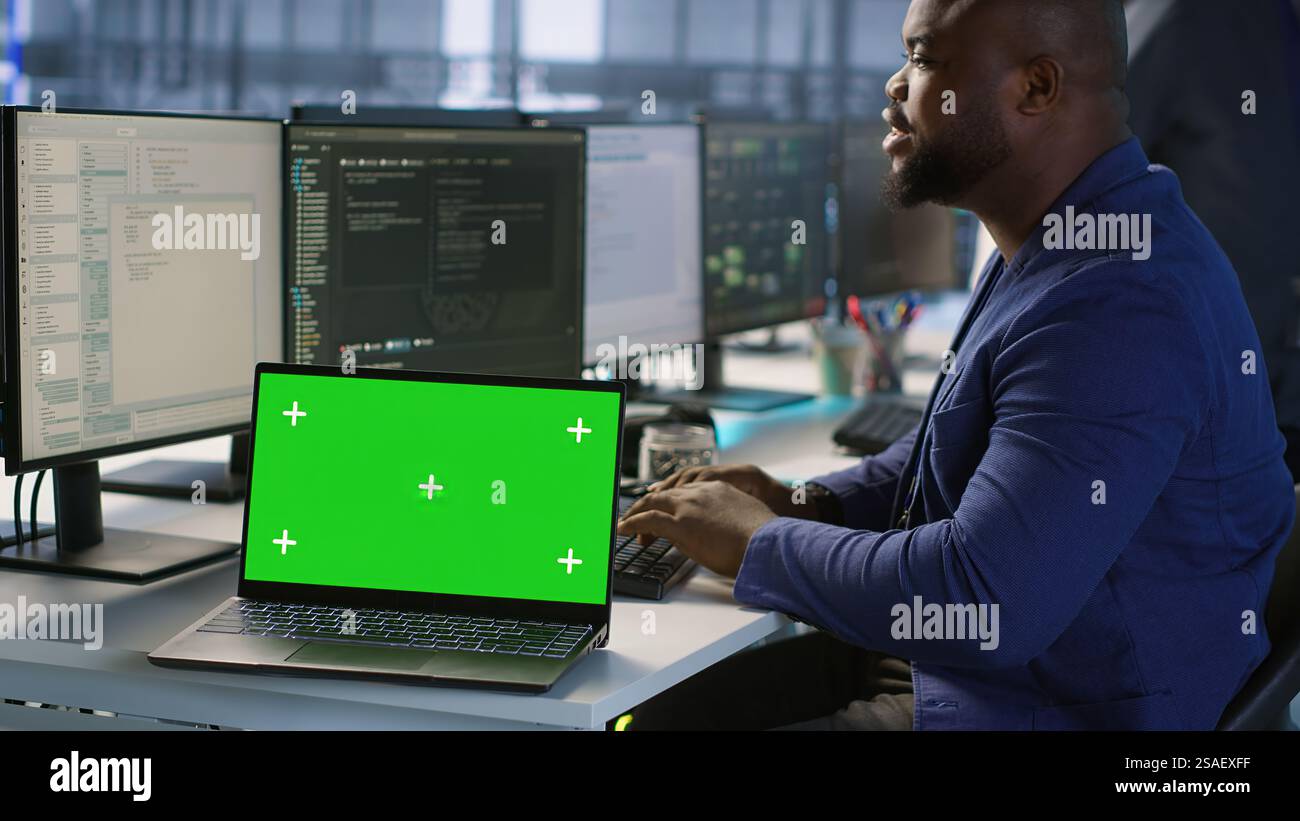Data center technician using chroma key laptop, maintaining company network infrastructure ...