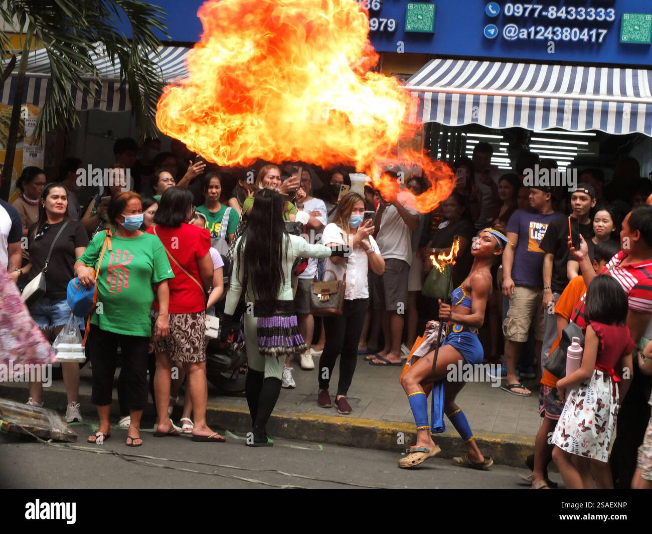 A fire-eater blows a large fire as spectators watch. Filipinos ...
